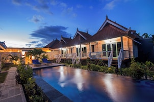 Um resort com vários quartos de hóspedes, piscina e um jardim bem cuidado.