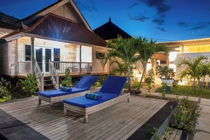 Um deck de madeira com duas cadeiras de lounge e uma escadaria que leva a um edifício.
