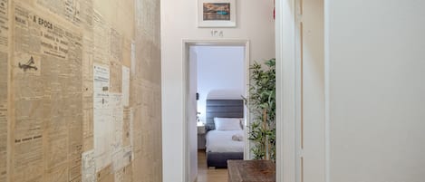 Um corredor com uma cama, uma planta e uma porta com o número 104.