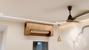 Ventilador de teto, iluminação embutida e um armário de madeira em um interior moderno.