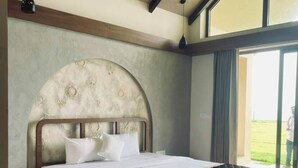 Quarto com cama grande, ventilador de teto, janela e vista para o exterior.