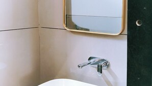 Casa de banho com uma pia branca, um espelho com moldura dourada e bancada preta.