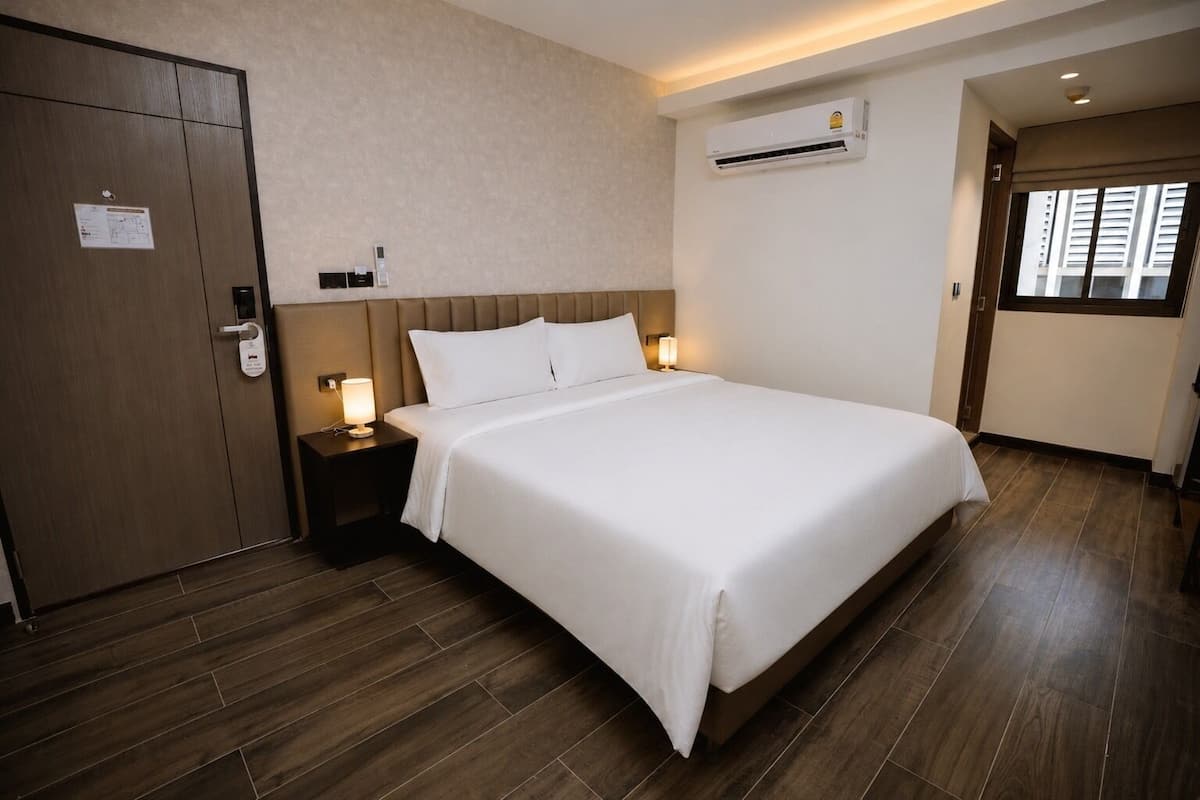 Quarto de hotel com cama, mesas de cabeceira, ar condicionado e uma porta.