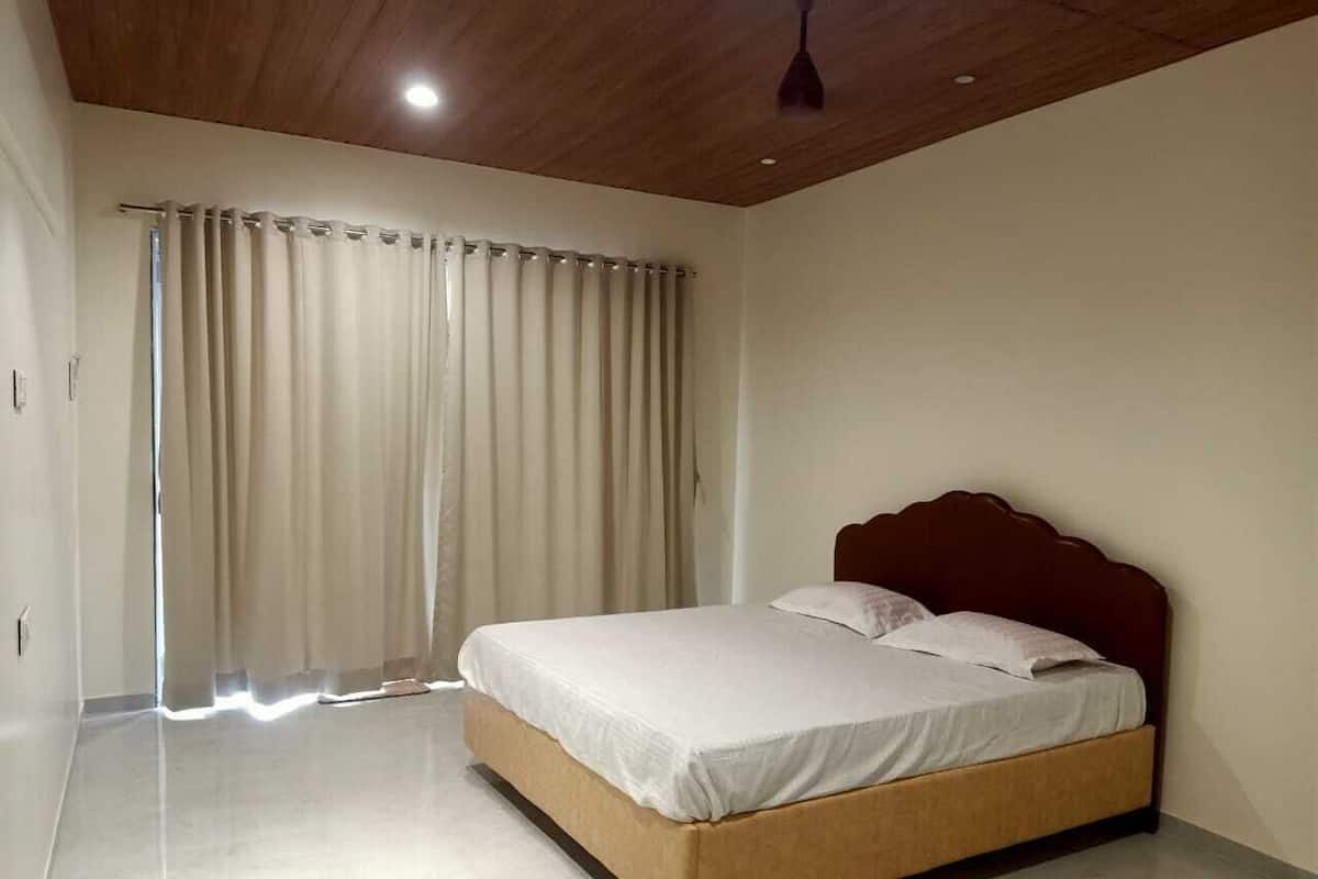 Quarto com cama, cortinas e teto de madeira.