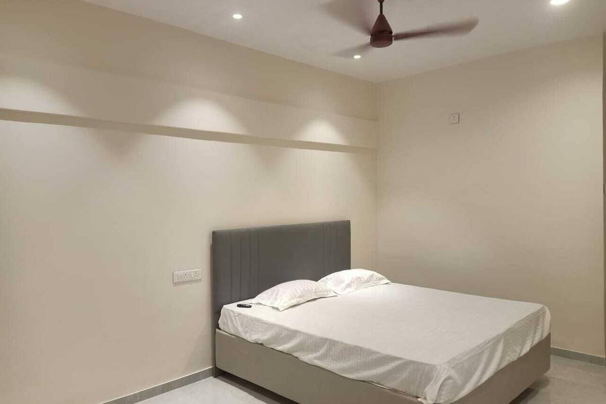 Quarto com cama, ventilador de teto, iluminação embutida e tomada na parede.