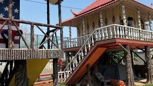 Um edifício com telhado vermelho e balaústres brancos, uma escadaria e uma bandeira.