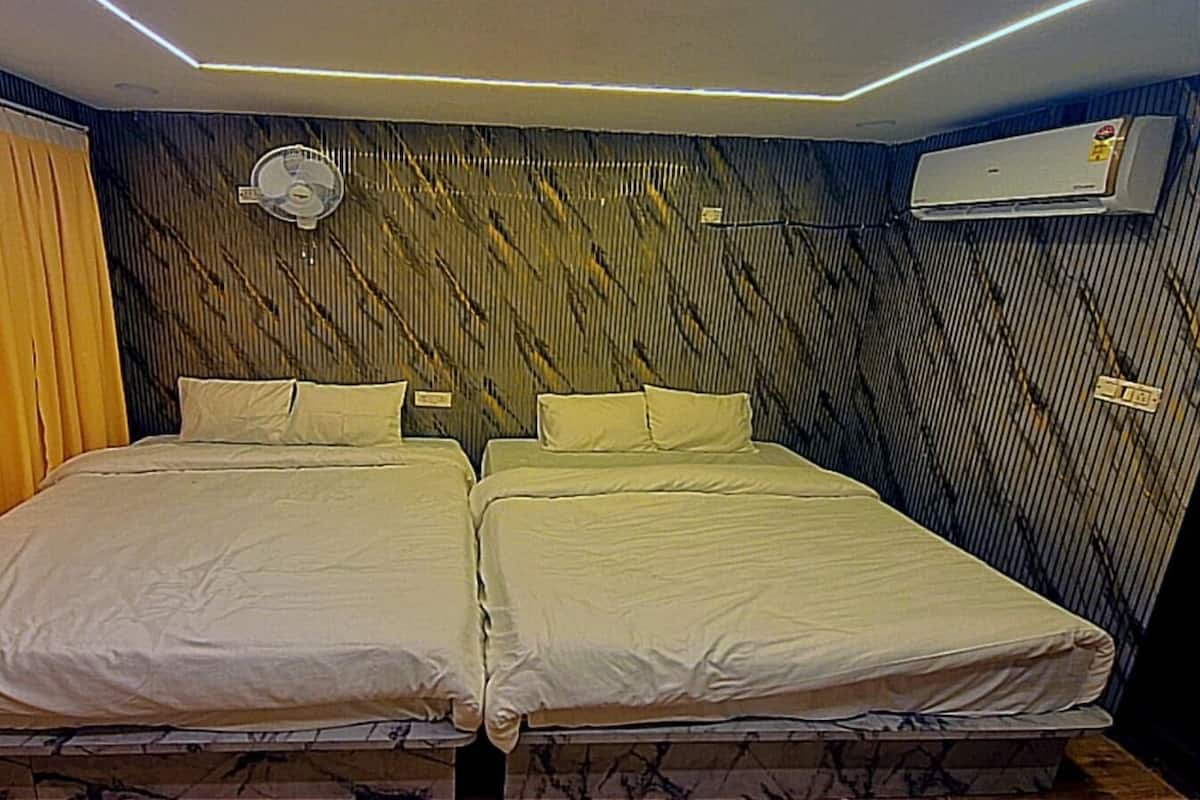 Quarto com duas camas, ventilador de teto, ar condicionado e parede estampada.