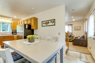 Uma cozinha moderna com armários de madeira, uma mesa de jantar com cadeiras e uma sala de estar com sofá e tapete.
