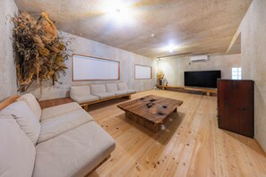 Uma sala de estar moderna com uma mesa de centro de madeira, um sofá, uma televisão e um objeto decorativo na parede.