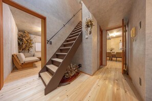 Um interior moderno com escada de madeira, sofá e área de jantar.