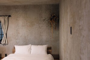 Quarto com cama, cortinas e planta na parede.