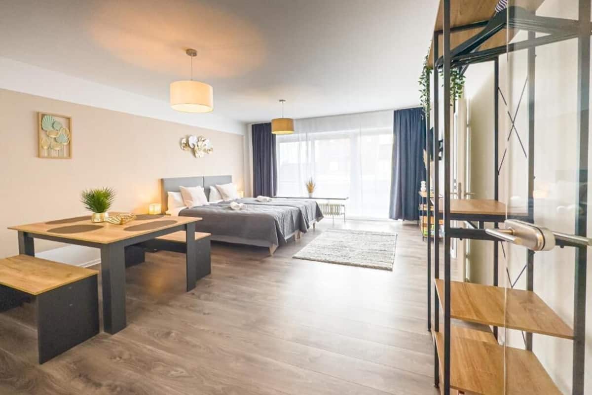 Quarto de hotel moderno com uma cama grande, uma escrivaninha e um separador de vidro.