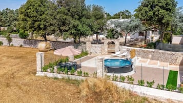 Uma área de piscina com hidromassagem, área de estar externa e uma parede de pedra.