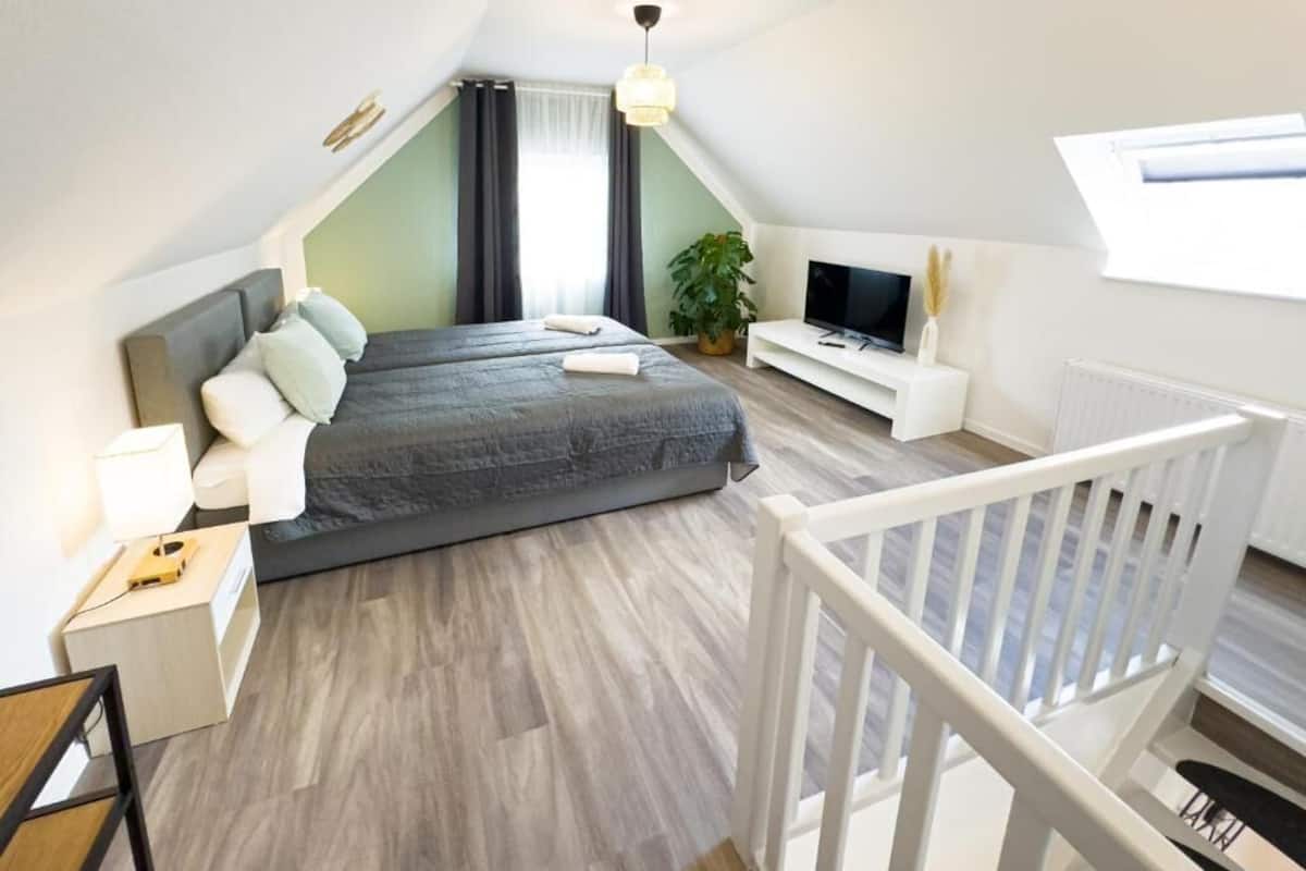 Quarto moderno com cama, televisão e grade branca.