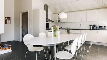Uma cozinha moderna com armários brancos, uma mesa de jantar redonda e cadeiras brancas.