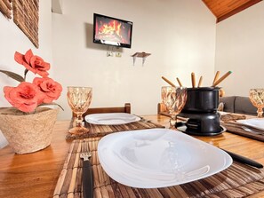 Uma mesa de jantar posta com pratos, talheres e um vaso decorativo com flores.