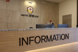 Bancada de recepção de hotel com uma placa indicando 'HOTEL JONGPANGSTAY' e uma placa de 'INFORMAÇÕES' abaixo.