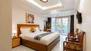 Quarto de hotel com cama, mesa de cabeceira, luminária, televisão e vista para o exterior.