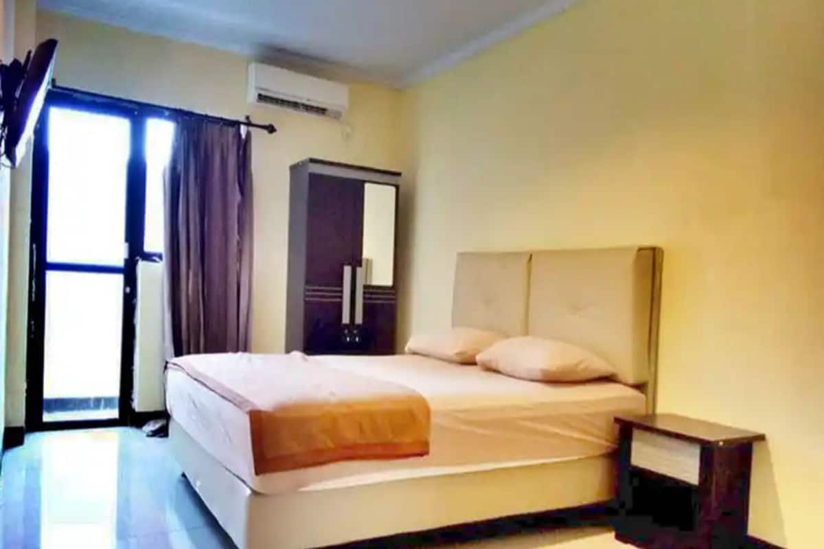 Quarto de hotel com cama, mesa de cabeceira e ar condicionado.