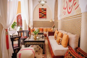 Um interior tradicional marroquino com um sofá, cadeiras, uma mesa de centro e elementos decorativos.
