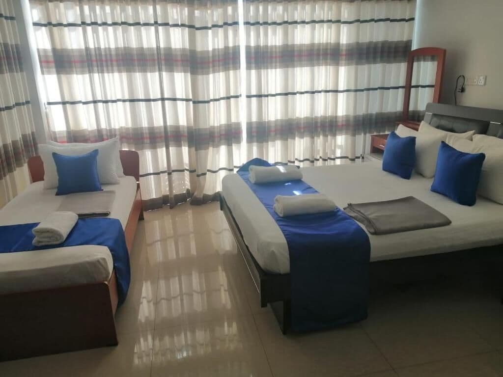 Quarto de hotel com duas camas de solteiro, uma cama grande e um sofá.