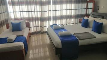 Quarto de hotel com duas camas de solteiro, uma cama grande e um sofá.