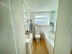 Uma casa de banho moderna com sanita, lavatório e banheira.