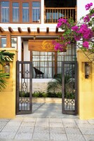 Entrada de um hotel boutique com pérgola de madeira, uma placa sobre a porta e um portão.