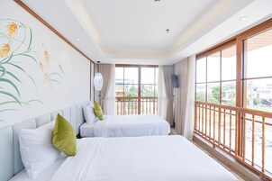 Quarto de hotel com duas camas, uma janela grande com vista e parede com um mural floral.