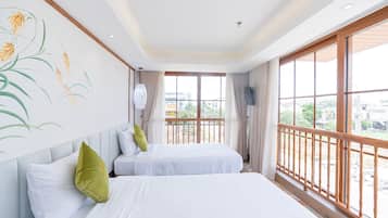 Quarto de hotel com duas camas, uma janela grande com vista e parede com um mural floral.
