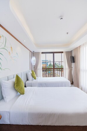 Quarto de hotel com duas camas, uma janela grande, uma luminária no teto e vista para o exterior.
