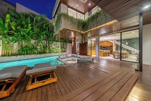 Uma casa moderna com deck de madeira, piscina e área de jantar.