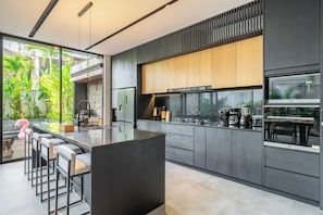 Cozinha moderna com ilha central, banquetas e área de jantar com mesa e cadeiras.
