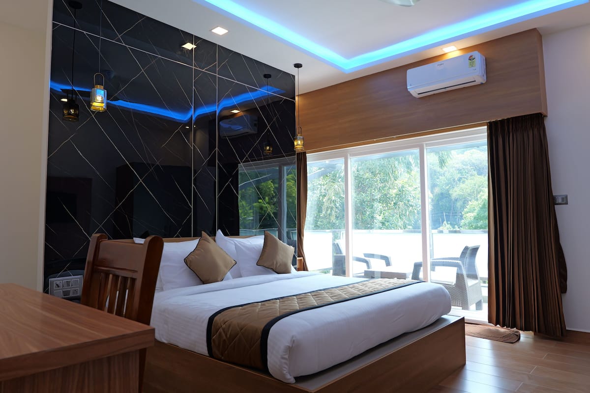 Quarto de hotel moderno com uma cama grande, uma mesa de jantar e vista para o exterior.