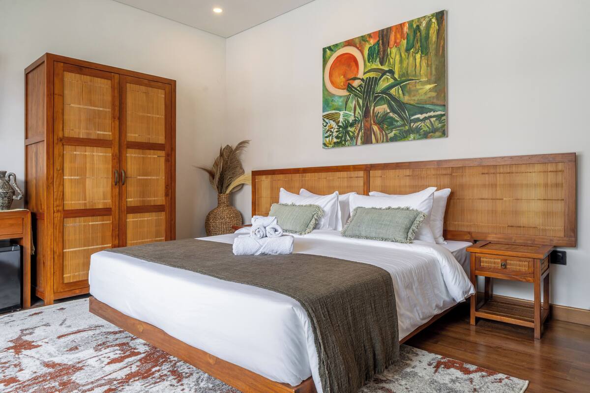 Quarto com cama grande, guarda-roupa de madeira e um quadro na parede.