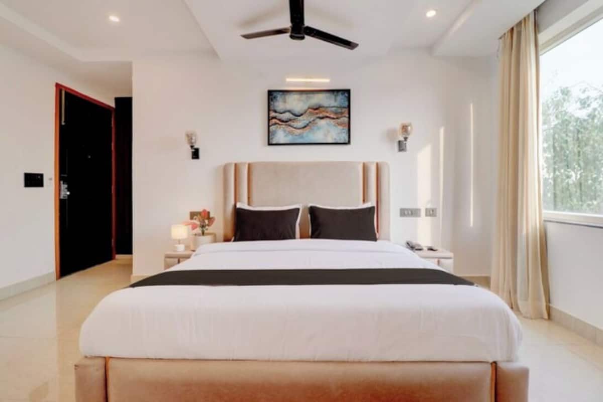 Quarto moderno com cama grande, ventoinha no teto, pintura na parede e janela com cortinas.