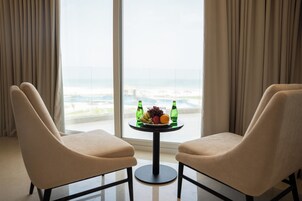 Quarto com duas cadeiras viradas para uma mesa com uma saladeira e garrafas, com vista.