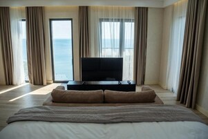 Quarto com cama, televisão e vista para o mar.