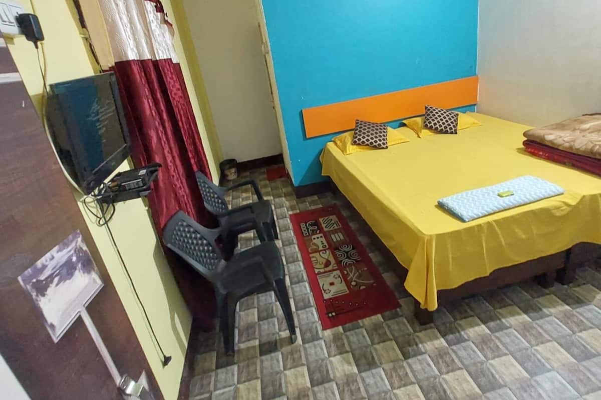 Um quarto pequeno com uma cama, uma escrivaninha, uma cadeira e um aparelho de ar condicionado.