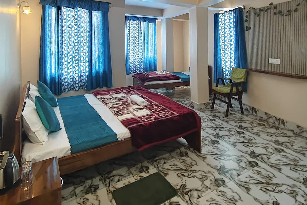Quarto com duas camas, uma cadeira, uma mesa e piso estampado.