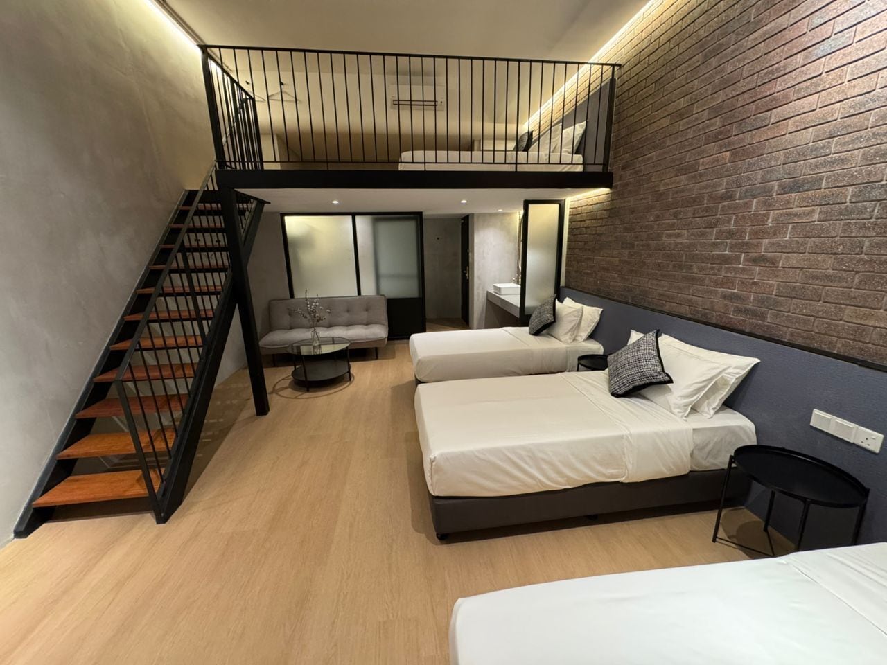 Quarto moderno no estilo loft, com cama beliche, escada e parede de tijolos.
