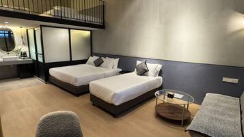 Quarto moderno com duas camas, uma mesinha, uma cadeira e varanda.