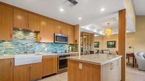 Uma cozinha moderna com armários de madeira, micro-ondas de aço inoxidável e painel de azulejos.
