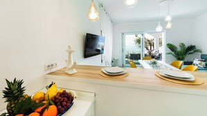 Cozinha moderna com uma fruteira, uma televisão de tela plana e luminárias pendentes.