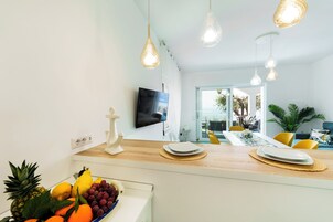Cozinha moderna com uma fruteira, uma televisão de tela plana e luminárias pendentes.
