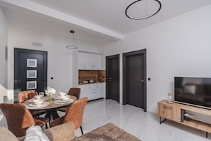 Uma sala de estar moderna com área de jantar, cozinha e TV.