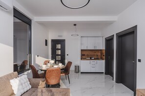 Um interior moderno com sala de jantar, cozinha e um sofá com almofada branca.