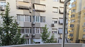 Varanda com vista para edifícios altos, chão de azulejos e porta de vidro.