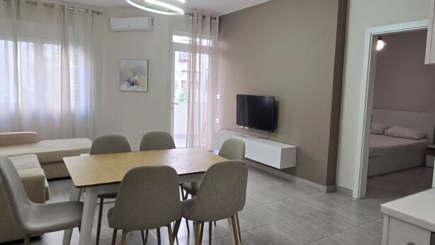 Uma sala de estar moderna com área de jantar, televisão de tela plana e sofá.