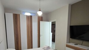 Quarto com cama, televisão e guarda-roupa.